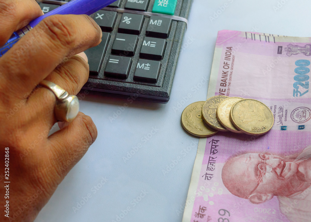 Woman checking account with calculator and holding a pen with Indian ...