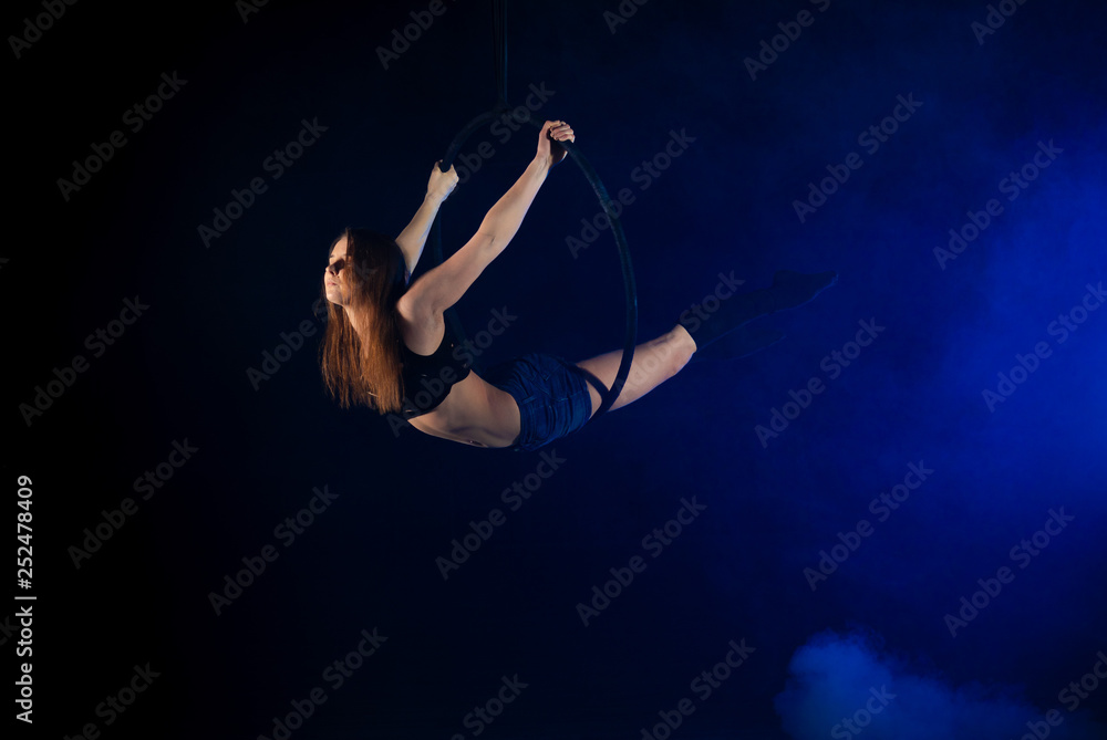 gymnast girl aerial acrobatics on the ring on the background of blue ...