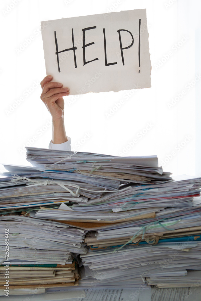 Person under a pile of papers with a hand holding a sign of help ...