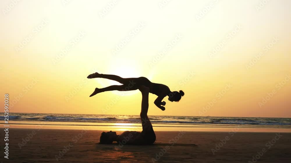 Silhouette of fit sporty couple practicing acrobatic yoga with partner ...