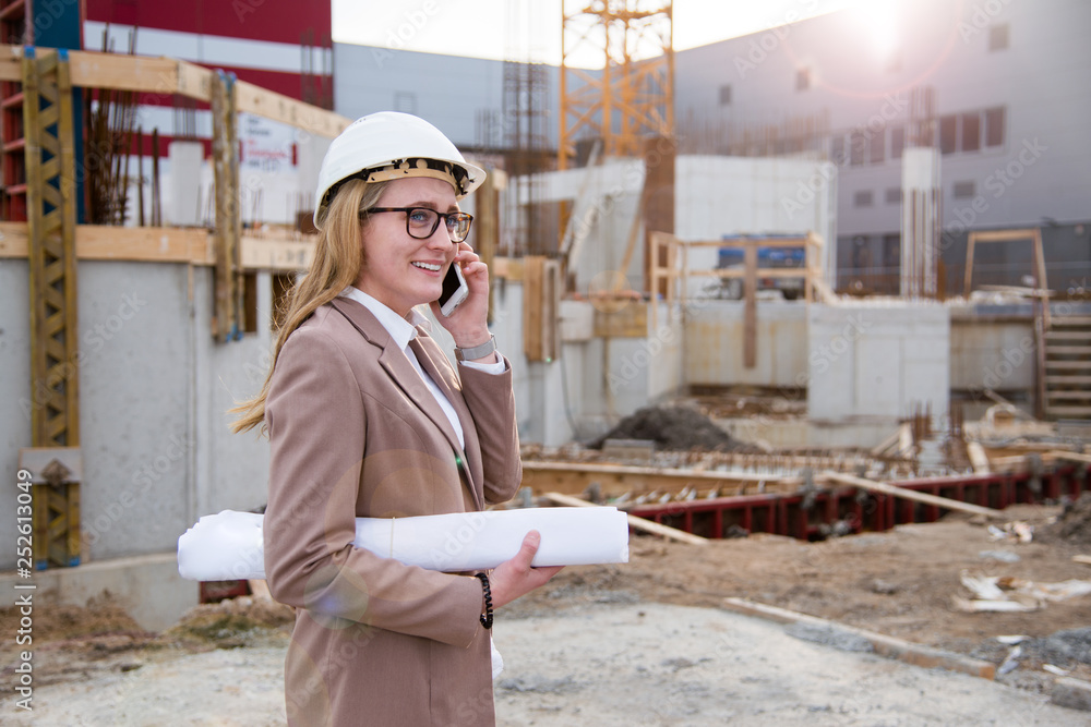 Frau als Architektin mit Helm, Bauplan, Plänen auf einer Baustelle mit ...
