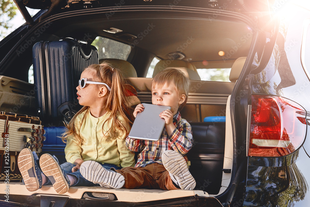 Little cute kids having fun in the trunk of a car with suitcases ...