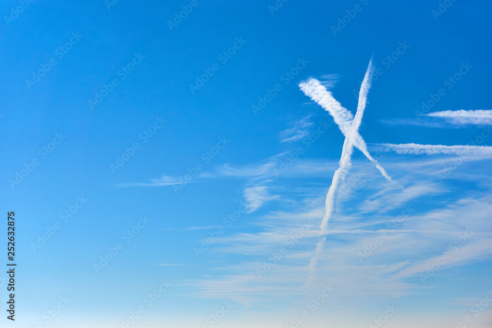 White clouds as an x shape sign against a saturated blue sky with copy ...