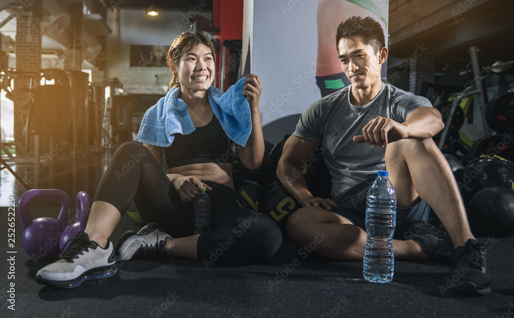 Fit people in exercise gear sitting together on the floor of a gym ...
