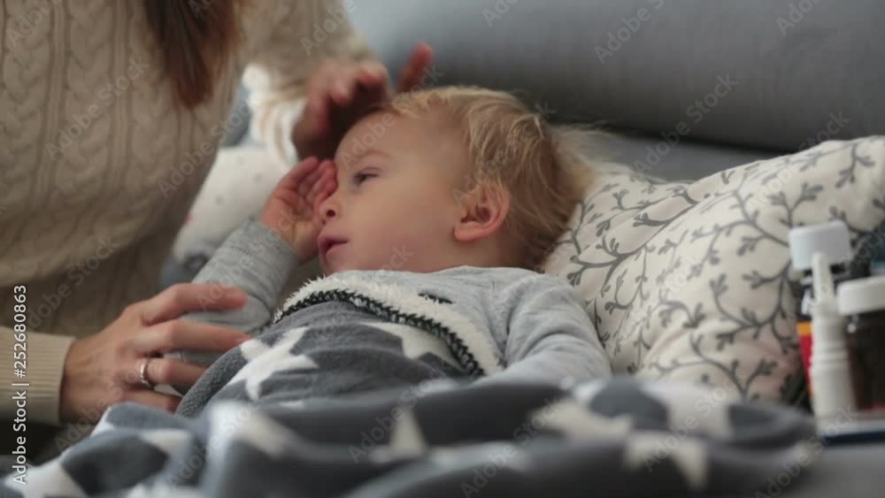 Sick child, toddler boy lying on the couch in living room with a fever ...