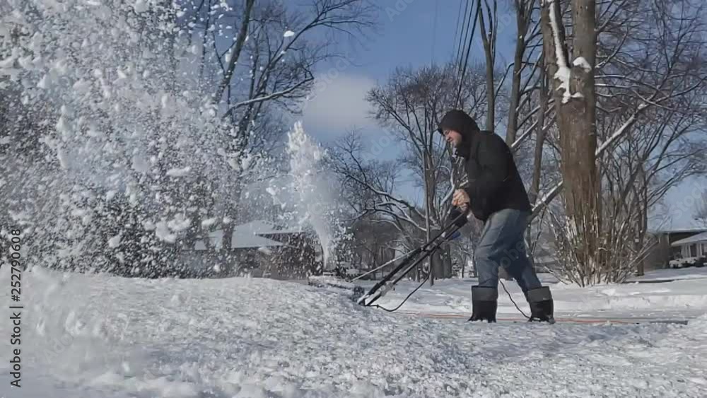 Super slow motion of Man in black jacket with hood removing snow from ...