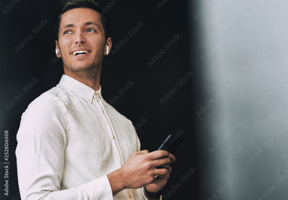 Handsome young man texting messages from his cellphone over black ...