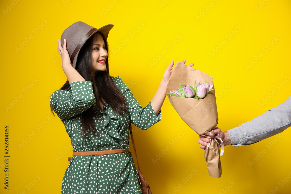 Woman receiving flowers for 8 March from young man on color background ...
