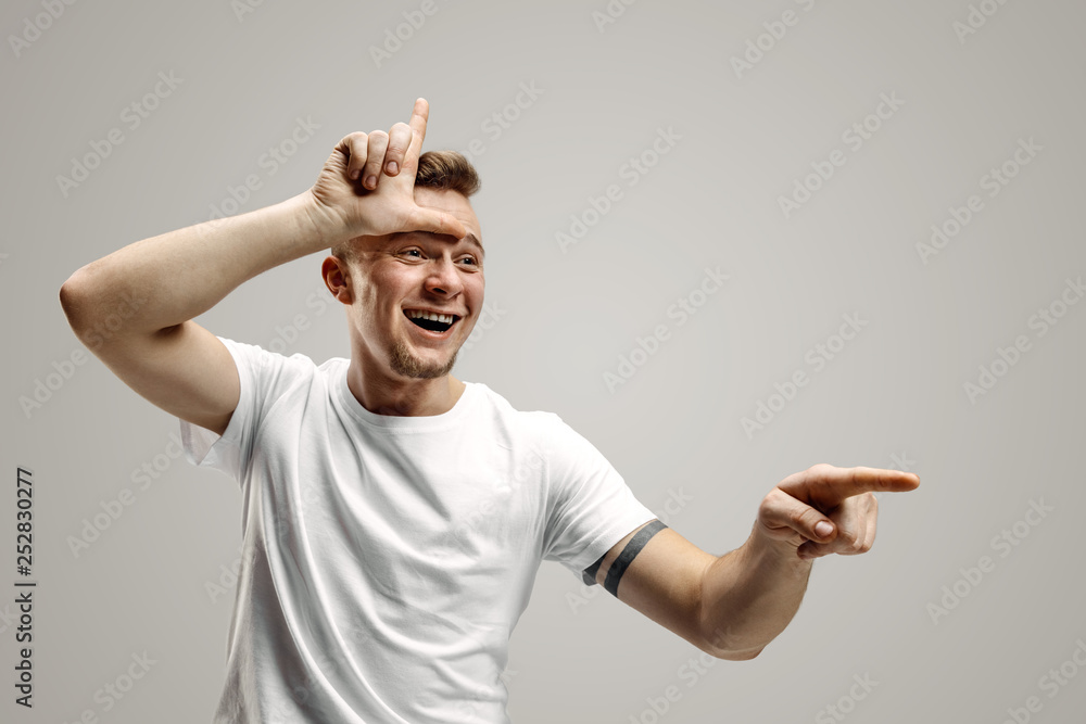 Losers go home. Portrait of happy guy showing loser sign over forehead ...