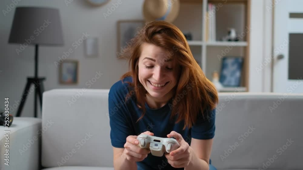 Determined girl playing a video game at home. Excited gamer woman ...