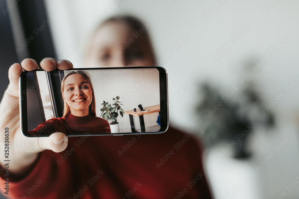 Positive young woman hold phone in hand and take selfie. She pose on ...