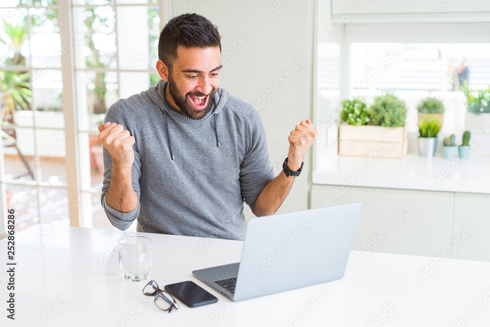 Handsome hispanic man working using computer laptop screaming proud and ...