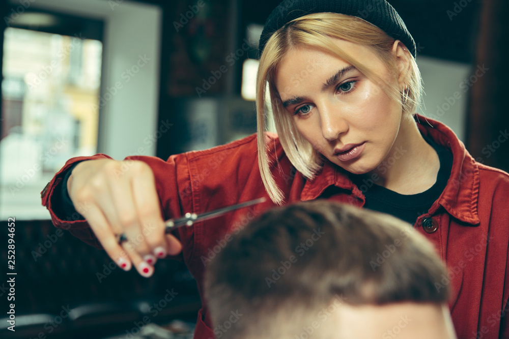 Client during beard shaving in barbershop. Female barber at salon ...