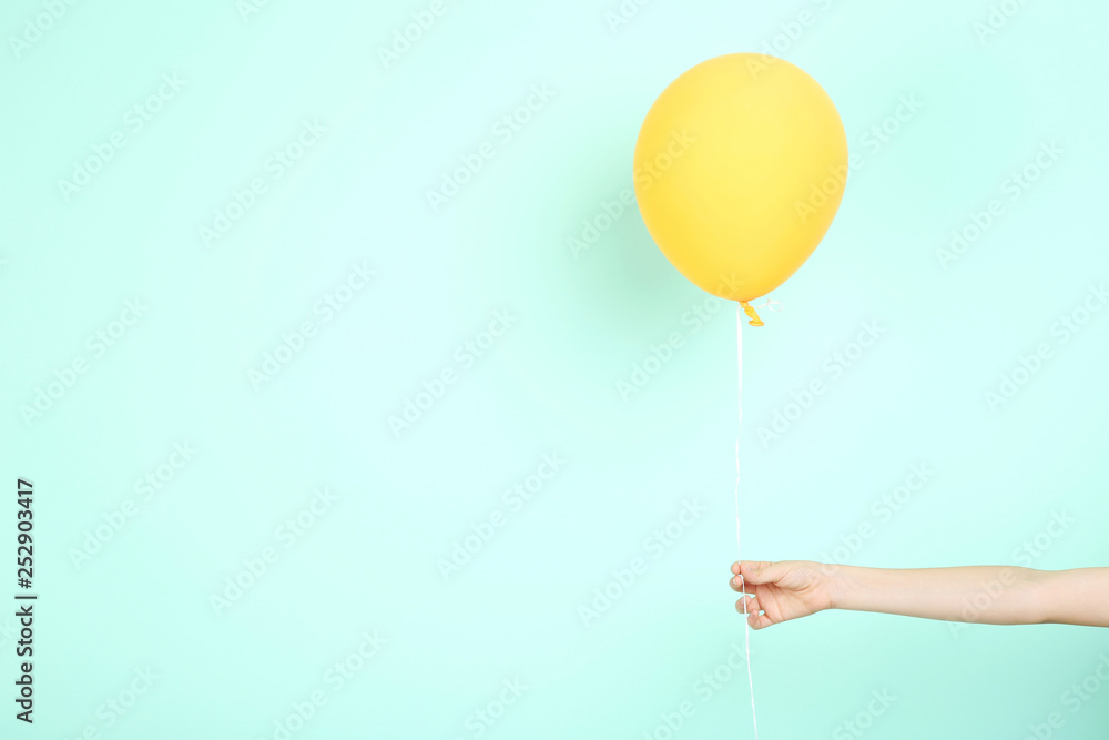 Female hand holding yellow balloon on mint background Stock Photo ...