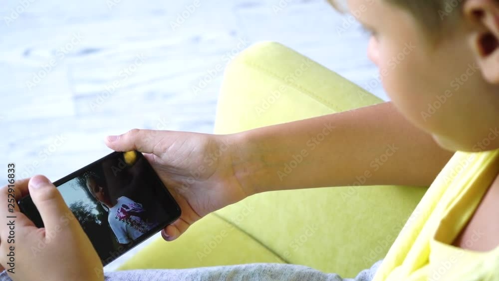 Closeup view of cute handsome young kid using modern mobile smart to ...