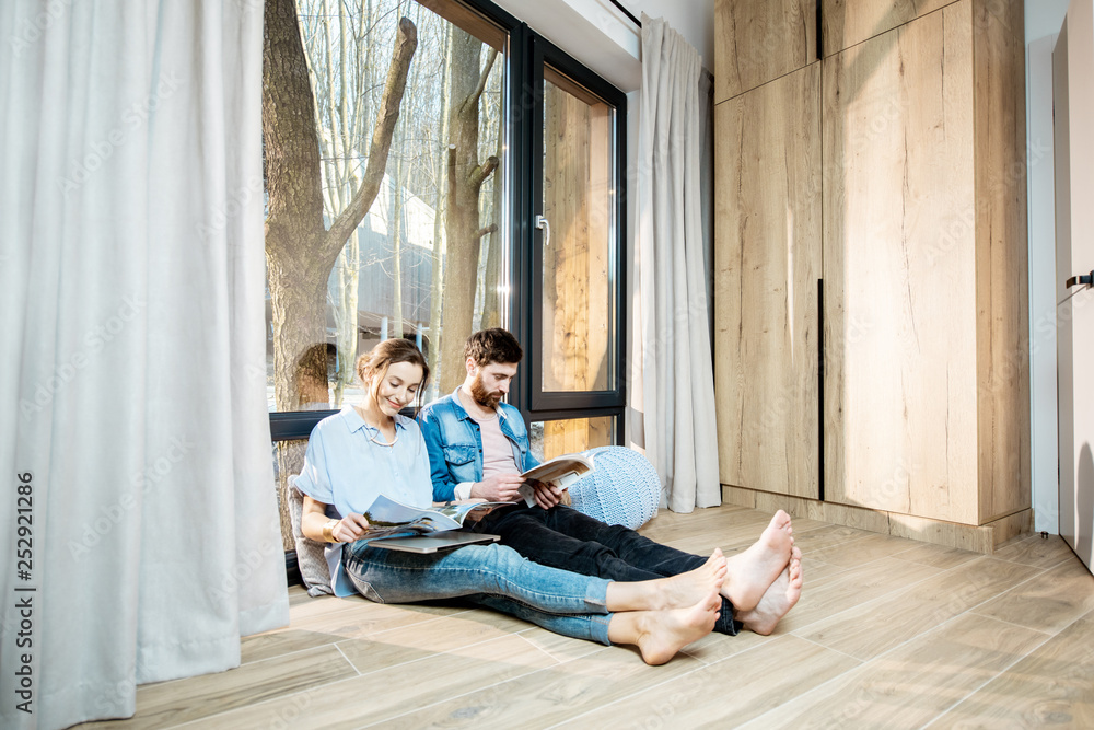 Happy couple sitting together on the floor near the window with ...