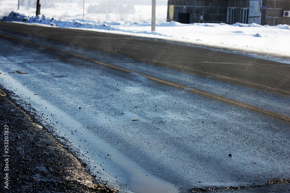 The spring sun heats asphalt after winter and evaporates. Wet road in ...