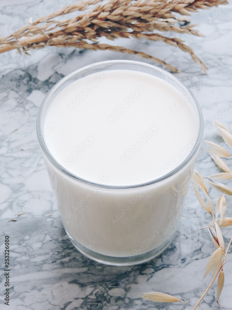 Pouring milk in the glass on blue background. Fresh milk pouring making ...