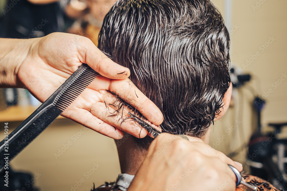 A professional hairdresser makes the design of the head, cuts hair with ...