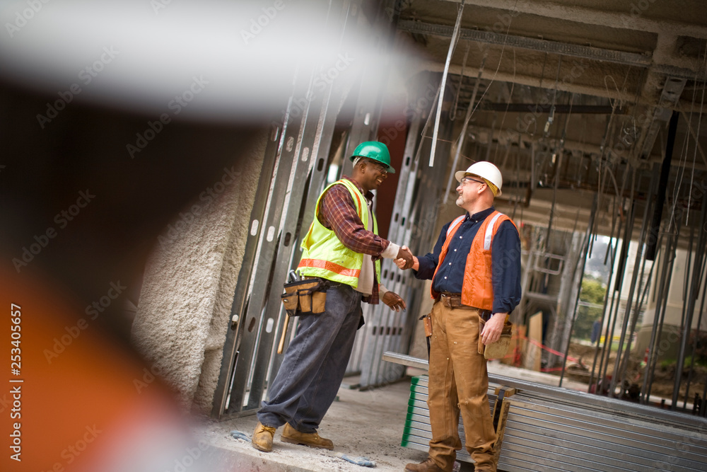 Foto de Mature male construction worker shaking hands with a mid-adult ...