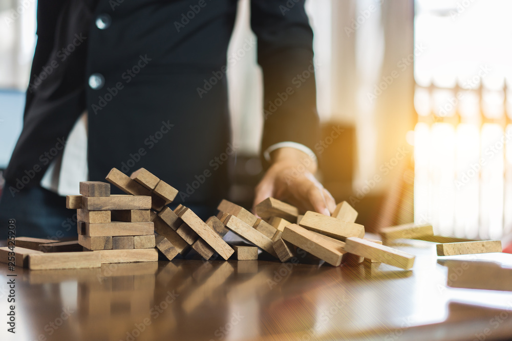 Hand of businessman pulling wood block fail on building tower at home ...