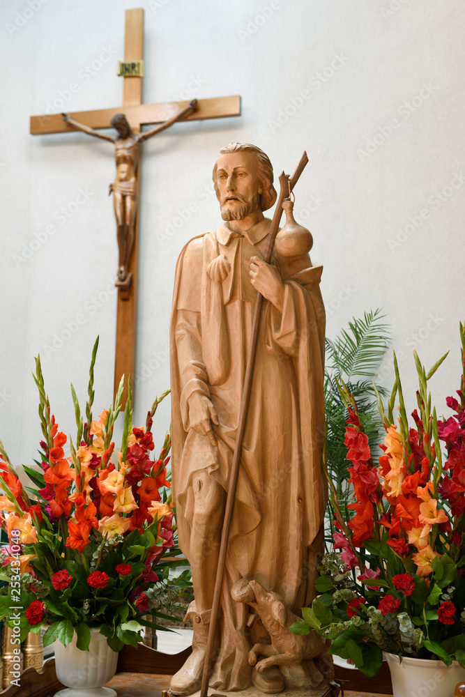 Carved wood statue of Saint Roch with plague bubo on thigh and dog with ...
