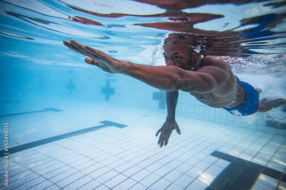 Underwater image of a male swimmer diving and swimming in a swimming ...