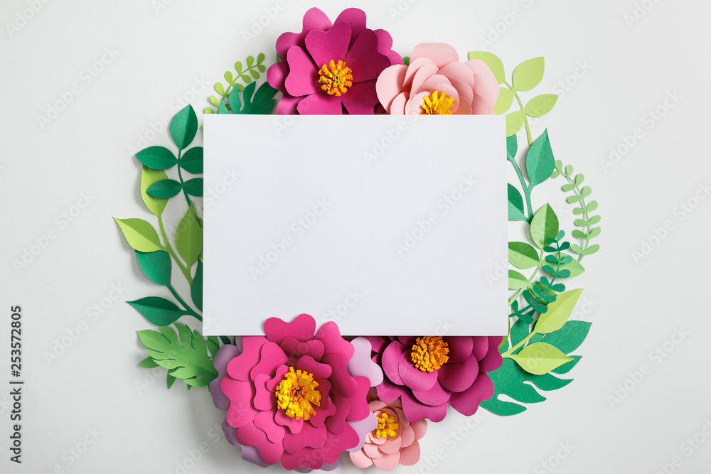 top view of white blank card near paper flowers with green leaves on ...