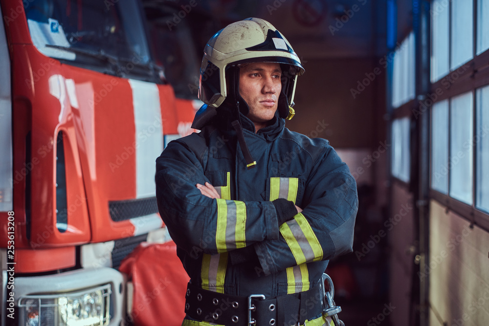 A brave fireman wearing protective uniform standing next to a fire ...