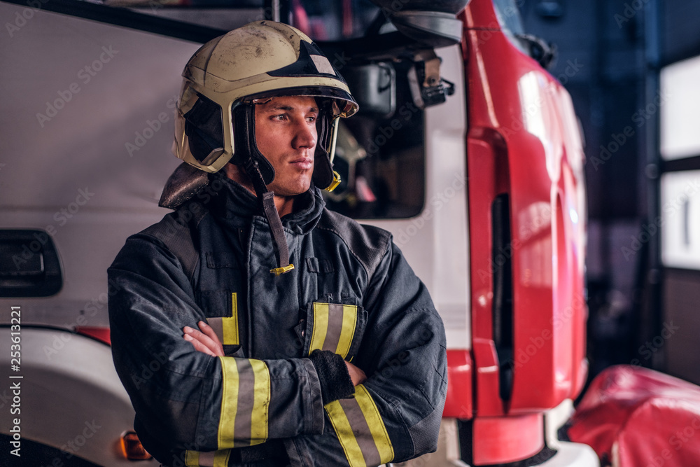 A brave fireman wearing protective uniform standing next to a fire ...