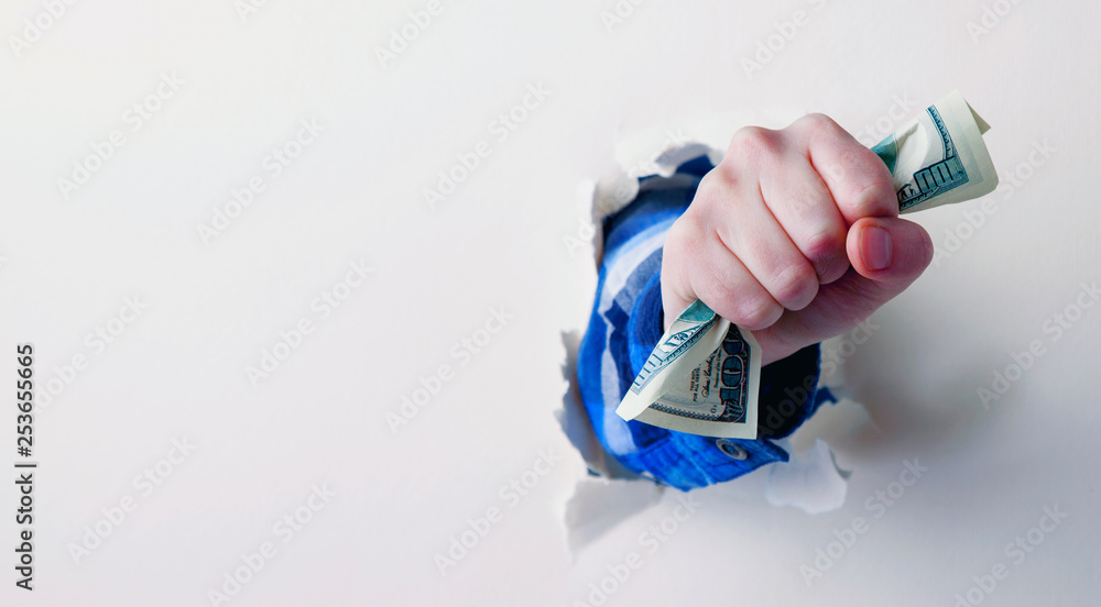 Hand give a crumpled banknote through torn white paper backgroundl as ...