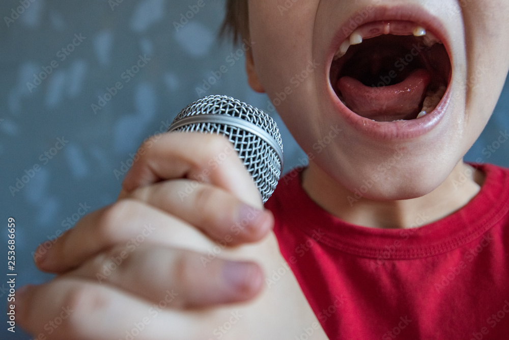 charming kid sings into microphone and opens her mouth wide with milk ...