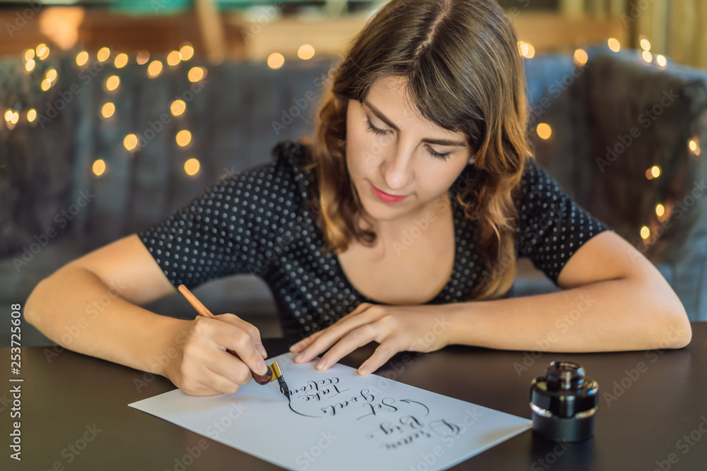 Calligrapher Young Woman writes phrase on white paper. Dream big, set ...