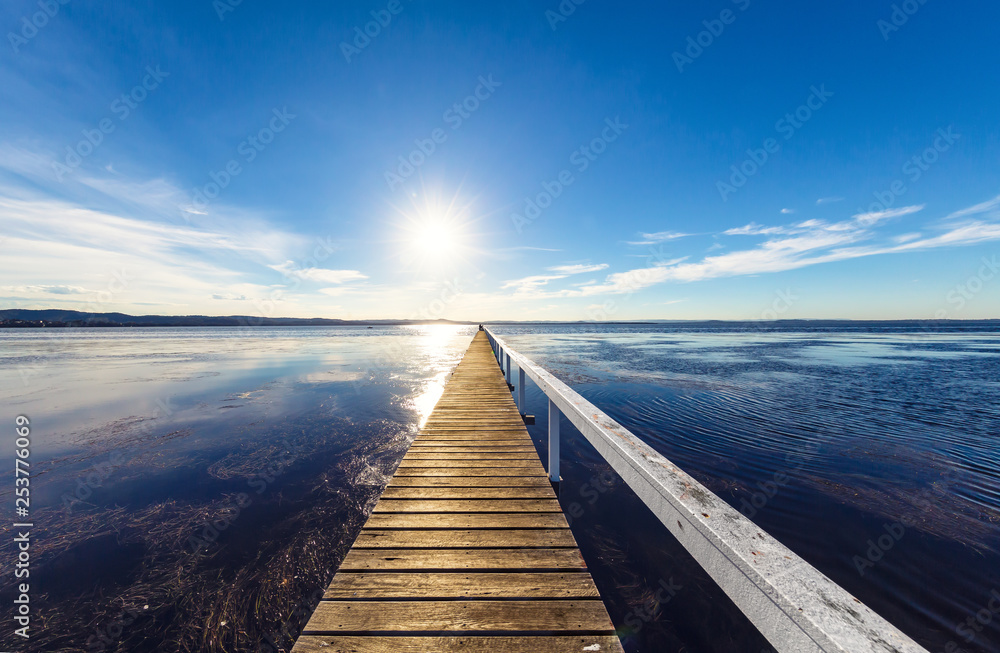 Perspective view to a vanishing point along the jetty into the sun and ...