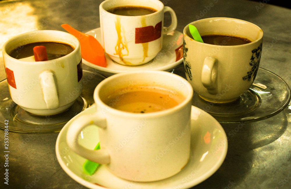 Four cups of coffees and hot chocolate served in white mugs on plate ...