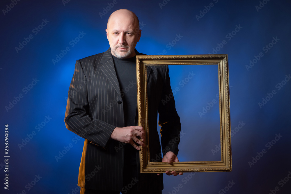 Bald man holding a photo frame in his hands. A man with a photo frame ...