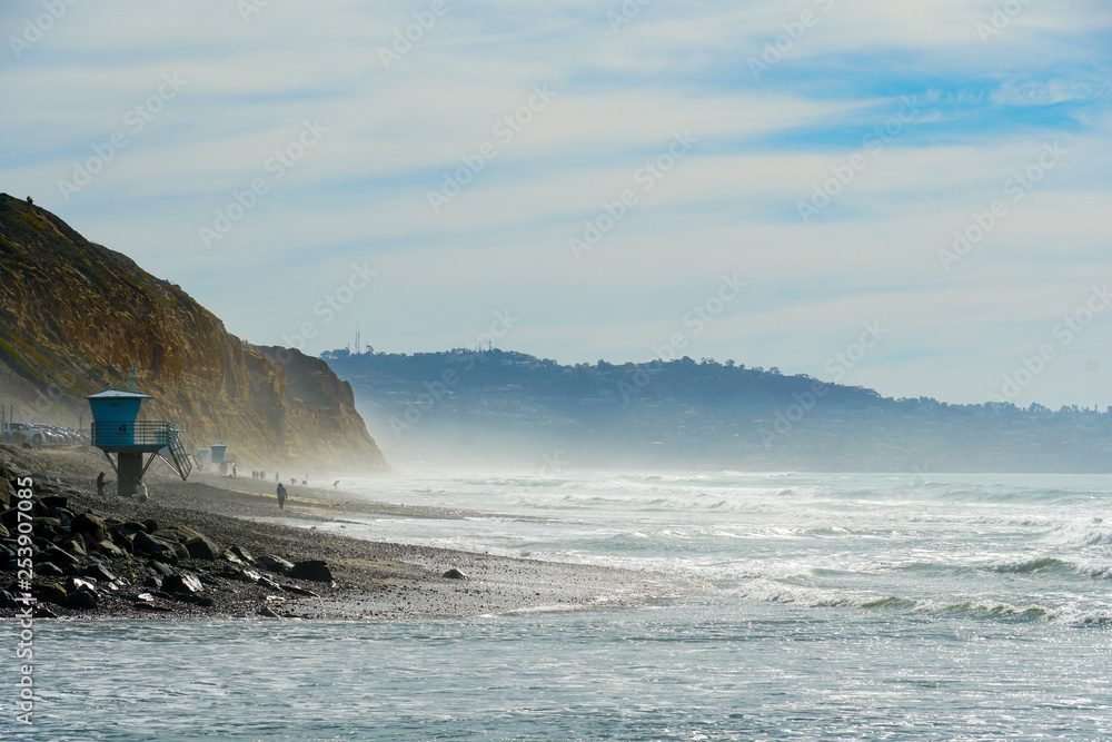 Foto Stock Rocky sand beach with clouded blue sky and blue lifeguard ...