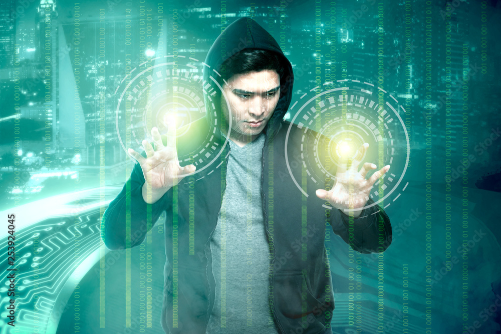 Young asian hacker in black hoodie touching virtual screen with binary ...