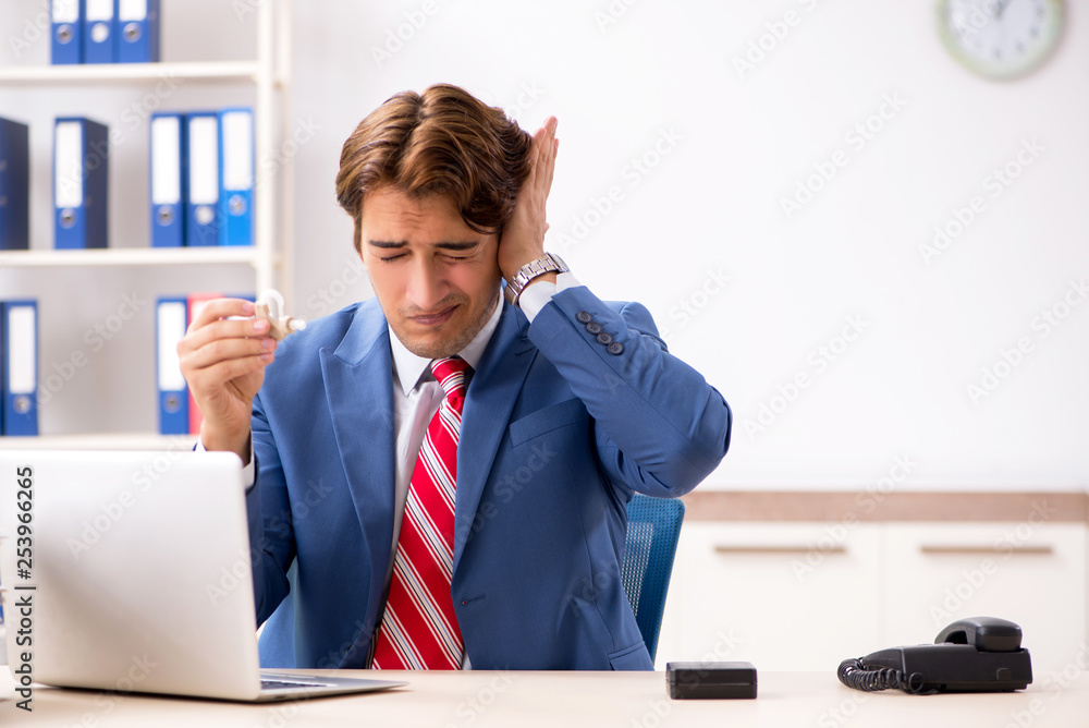 Deaf employee using hearing aid in office Stock Photo | Adobe Stock