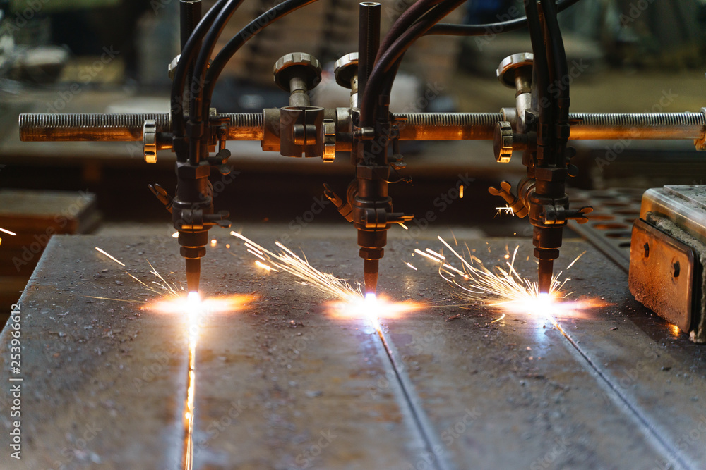The machine cuts metal sheets with gas. Flying spray molten metal. Side ...