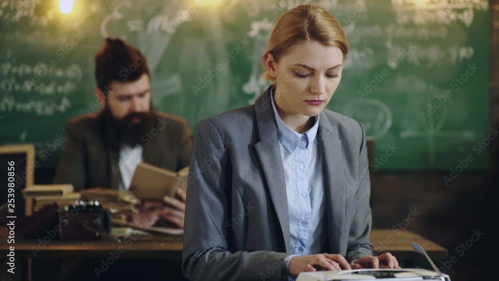 Woman wearing suit typing text on typewriter on background of school ...
