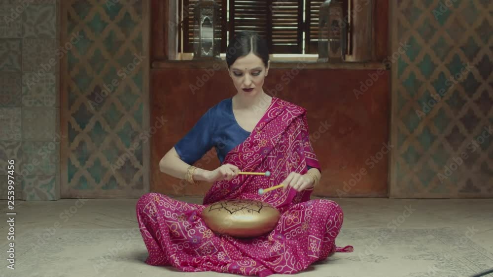 Attractive female performing traditional indian music using hank drum ...