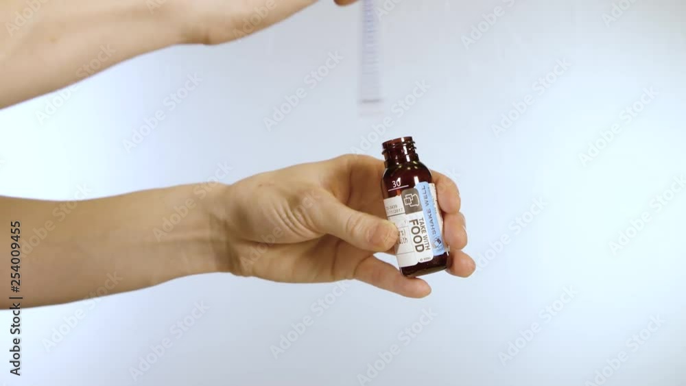 Measuring out liquid medication from bottle with take with food label ...