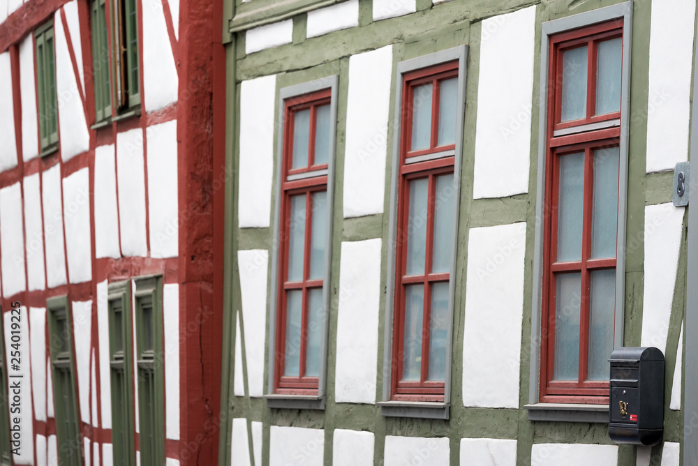 old and askew half-timbered house with green and red wooden beams and ...
