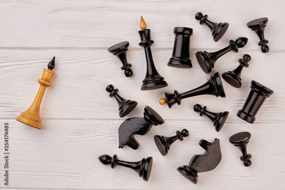 Black chess pieces near brown chess queen. Brown queen lying separately ...