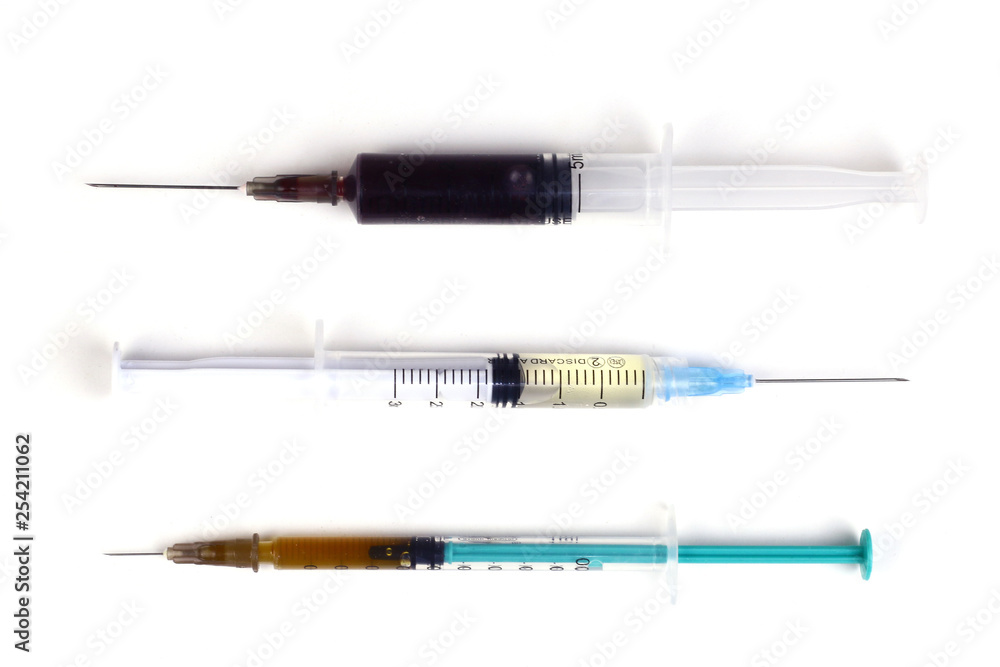 Three different sized and type of syringe with different color liquids ...