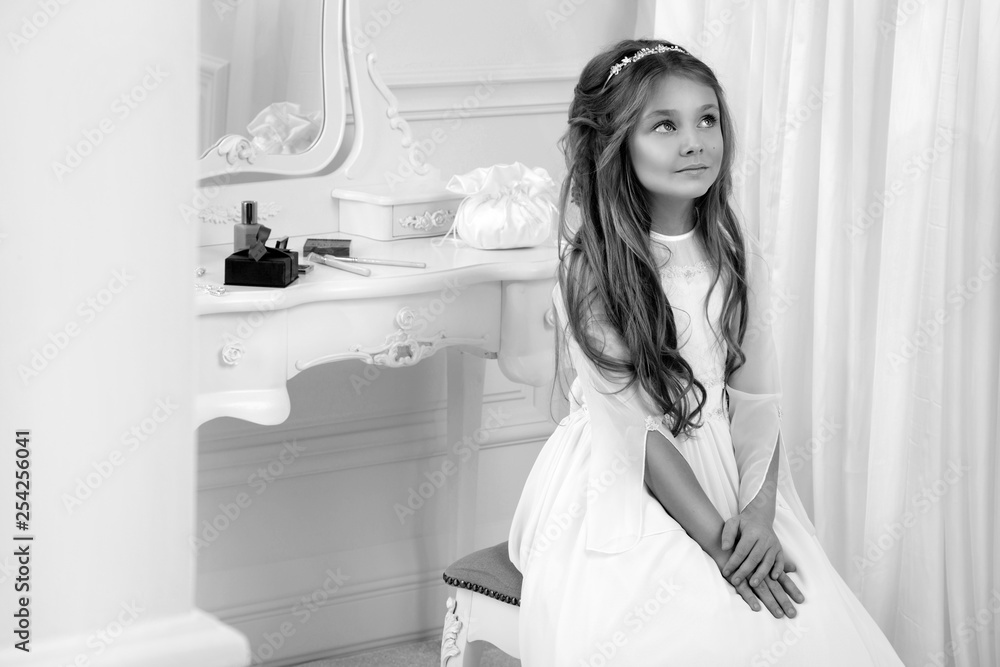 Portrait of cute little girl on white dress and wreath on first holy ...