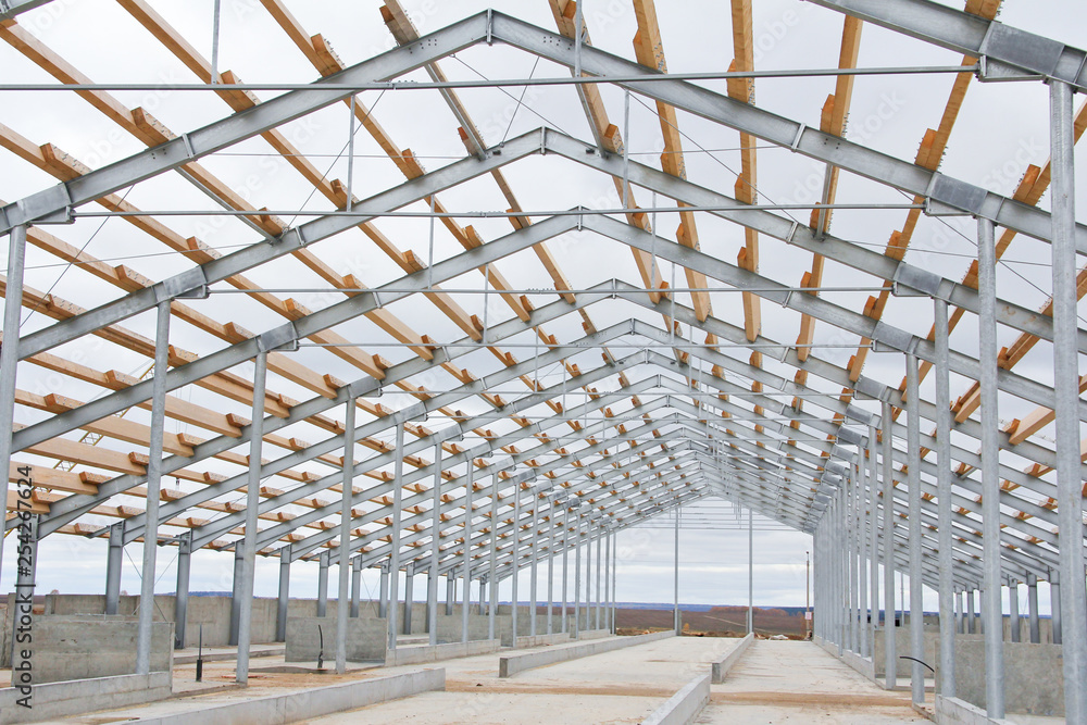 The construction of the new barn. Wooden beams on a metal frame ...