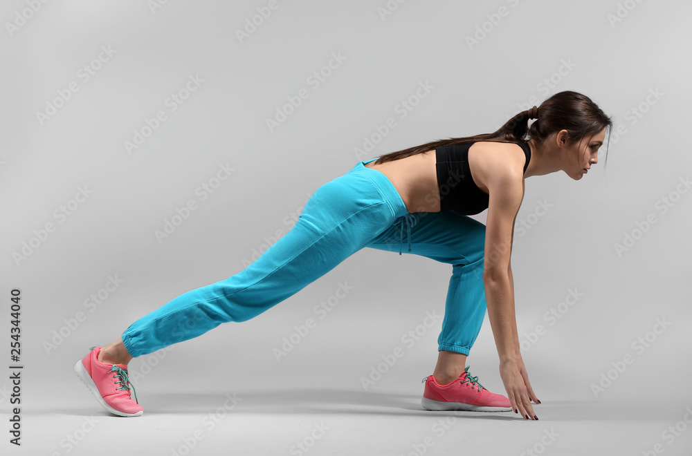 Sporty young woman in crouch start position against light background ...