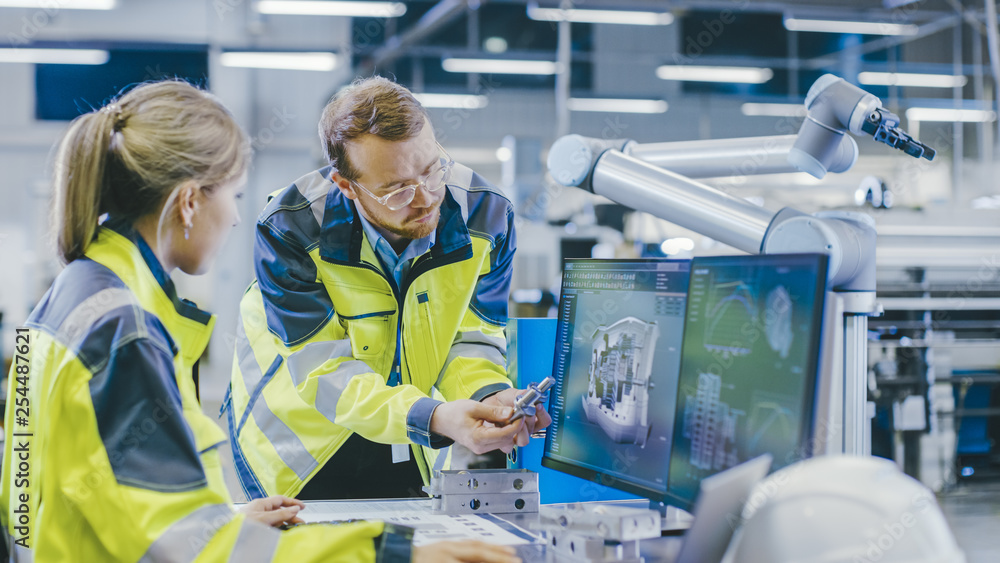 At the Factory: Male Mechanical Engineer Holds Component and Female ...